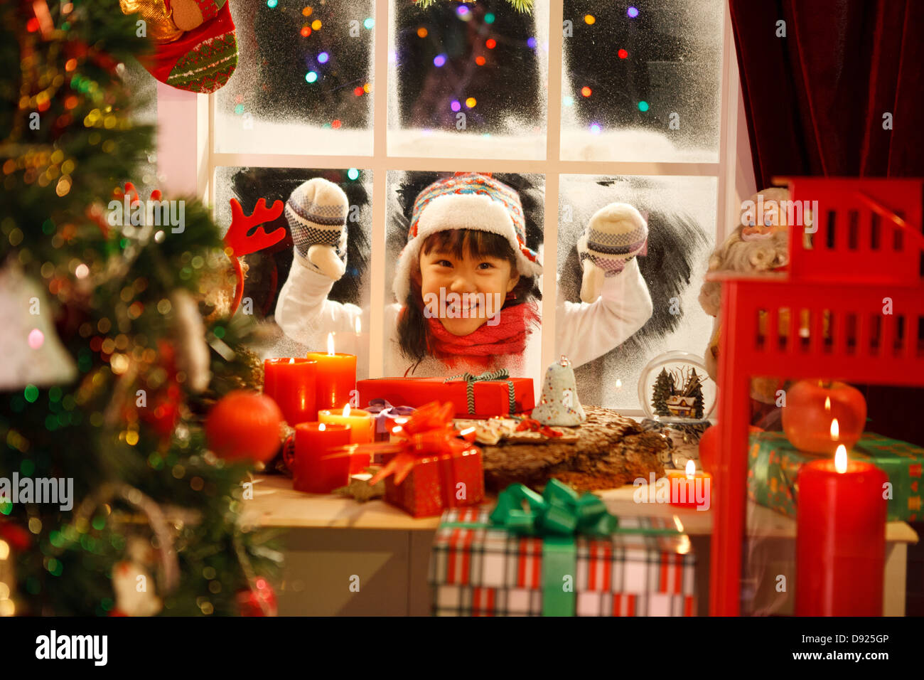 Girl looking at Christmas gift through window Stock Photo - Alamy