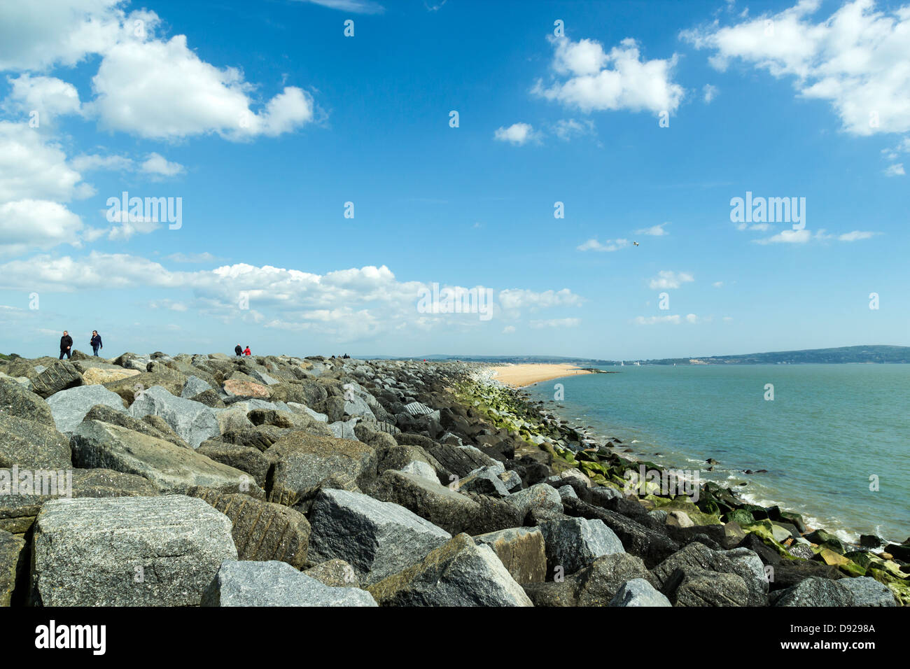 Walkers on Hurst Spit near Barton On Sea with coastal defenses ...
