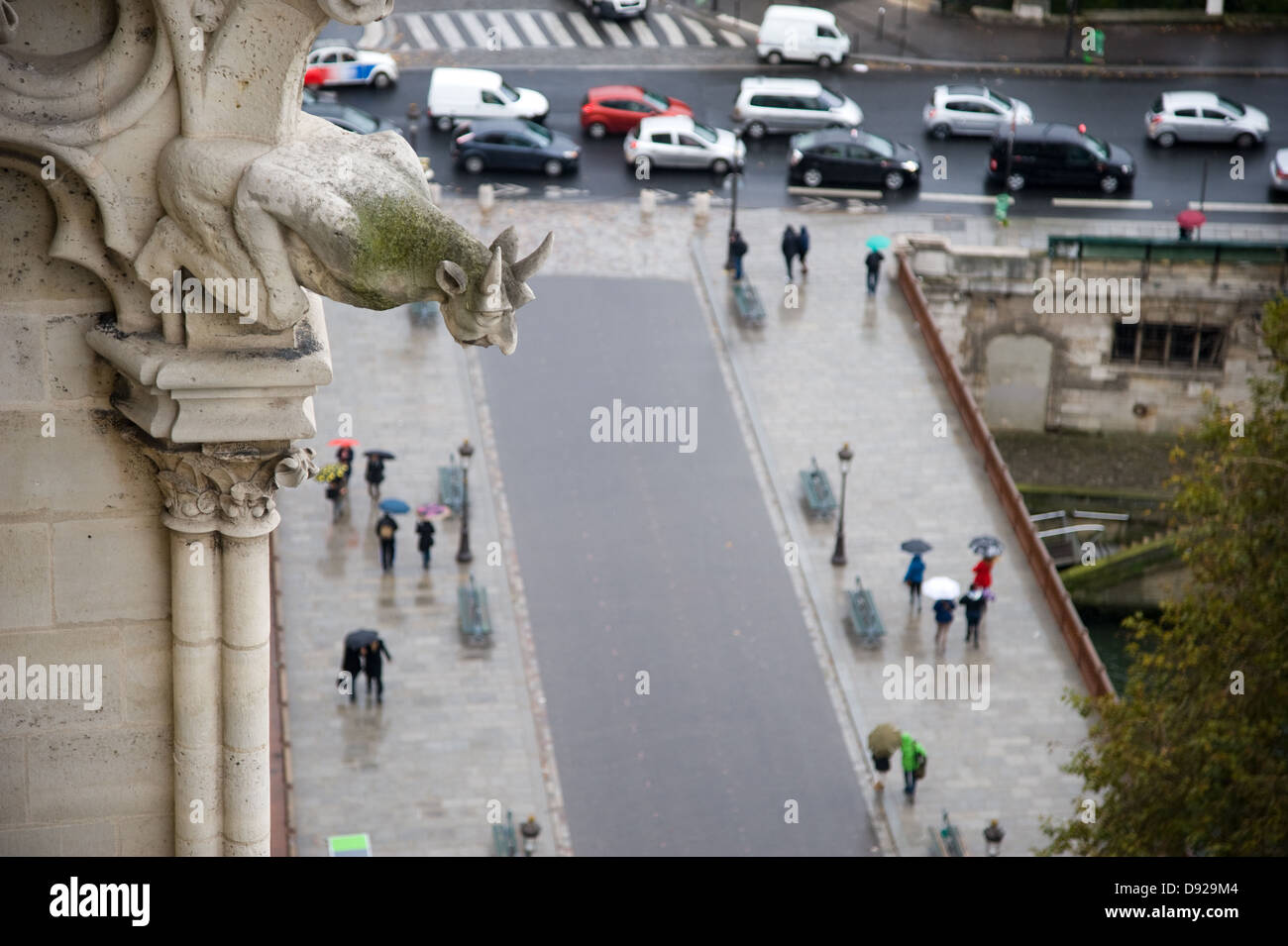 A gargoyle overlooking pedestrians walking in the rain in paris Stock ...