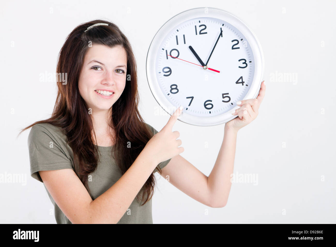 time concept: teen girl pointing to clock Stock Photo - Alamy