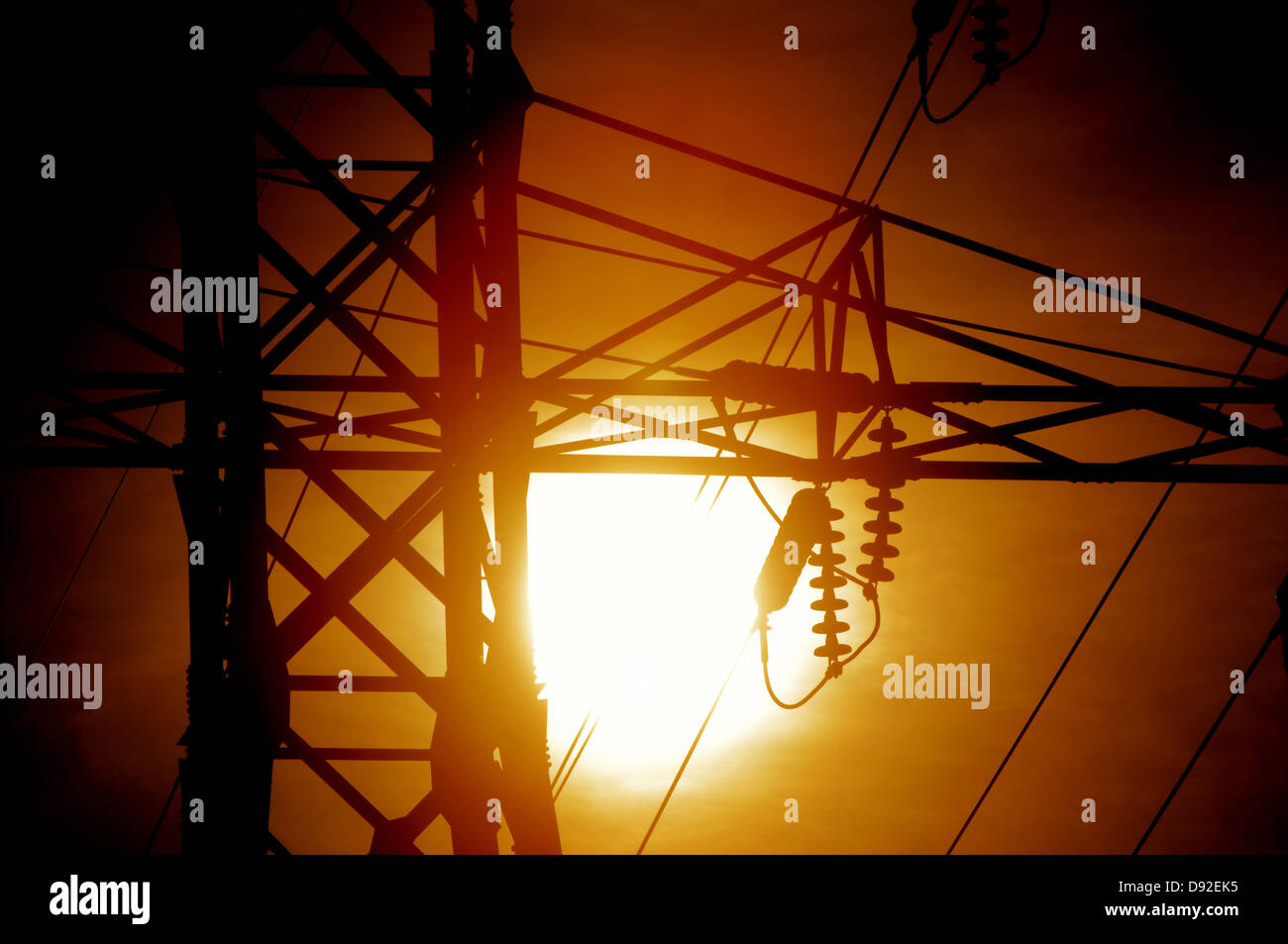 Hydro power lines and tower silhouetted against the rising or setting ...