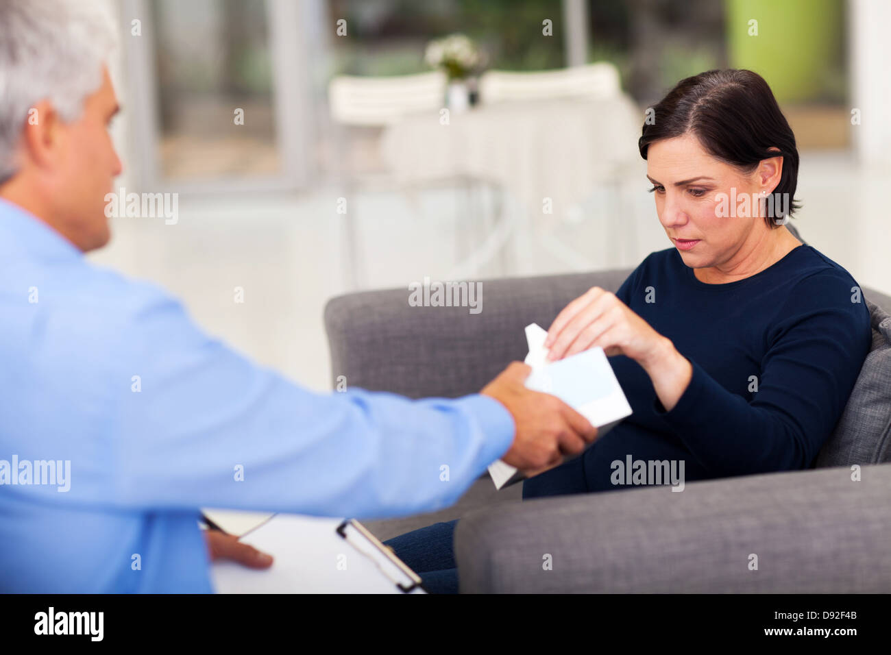 understanding therapist handing tissue to an upset middle aged patient ...