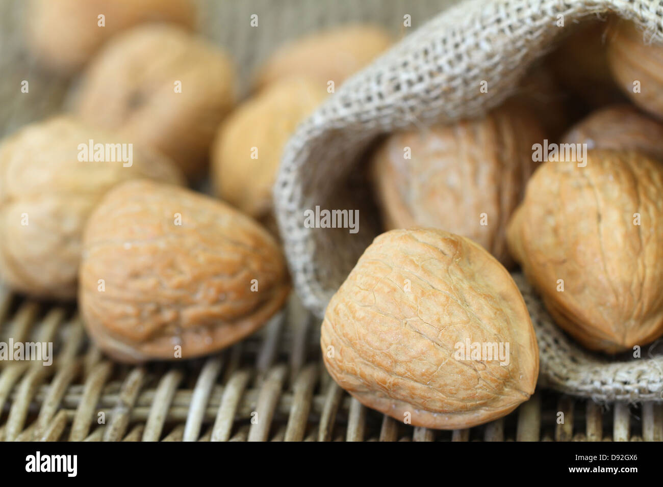 Whole walnuts in jute bag on wicker surface, close up Stock Photo - Alamy
