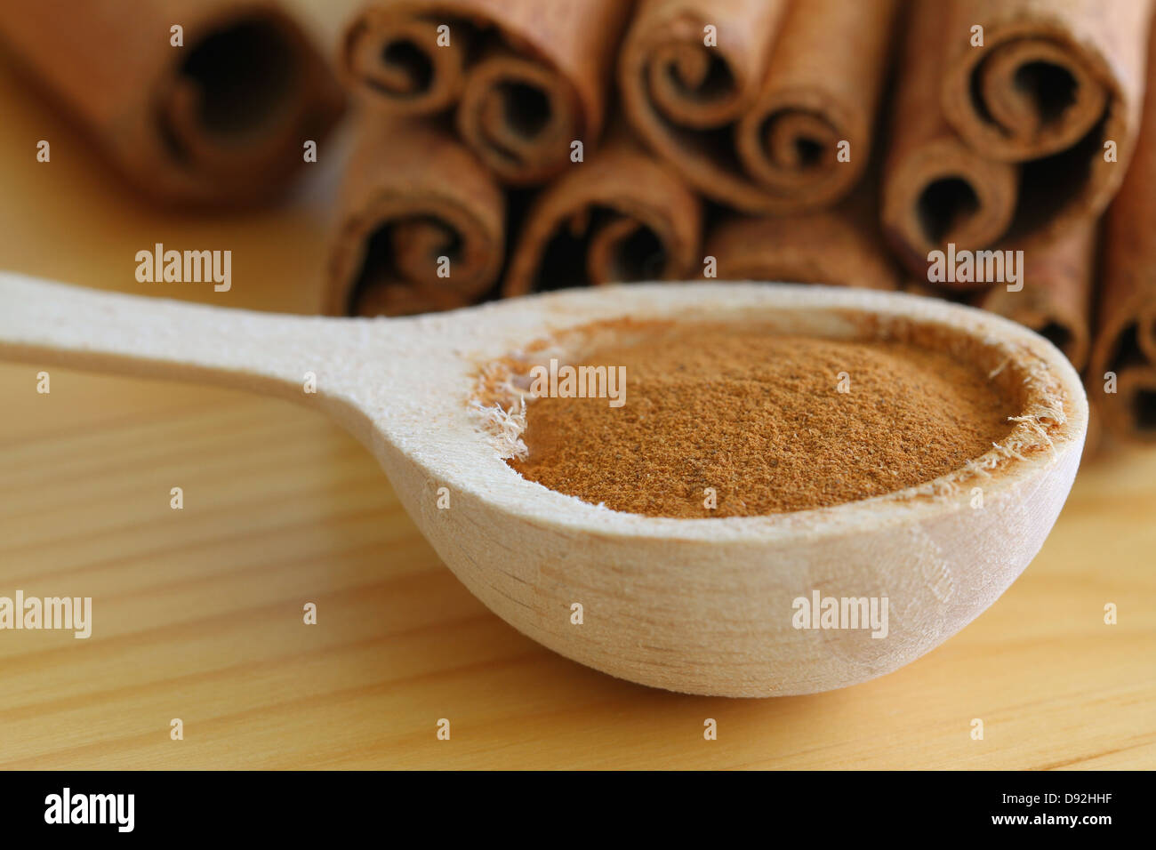 Cinnamon powder on wooden spoon with cinnamon sticks in the background ...