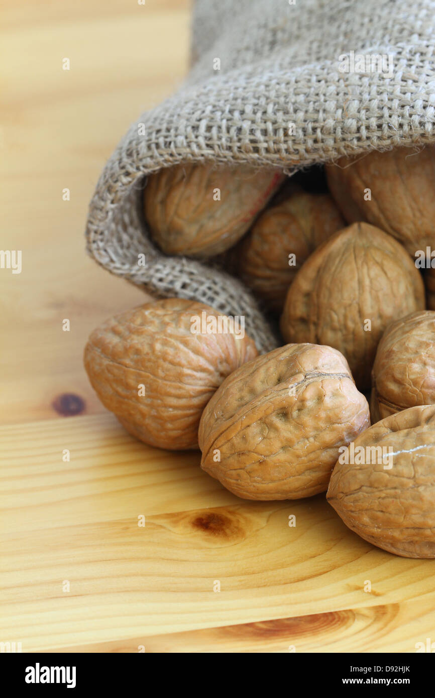 Whole walnuts in jute bag on wooden surface, close up Stock Photo - Alamy