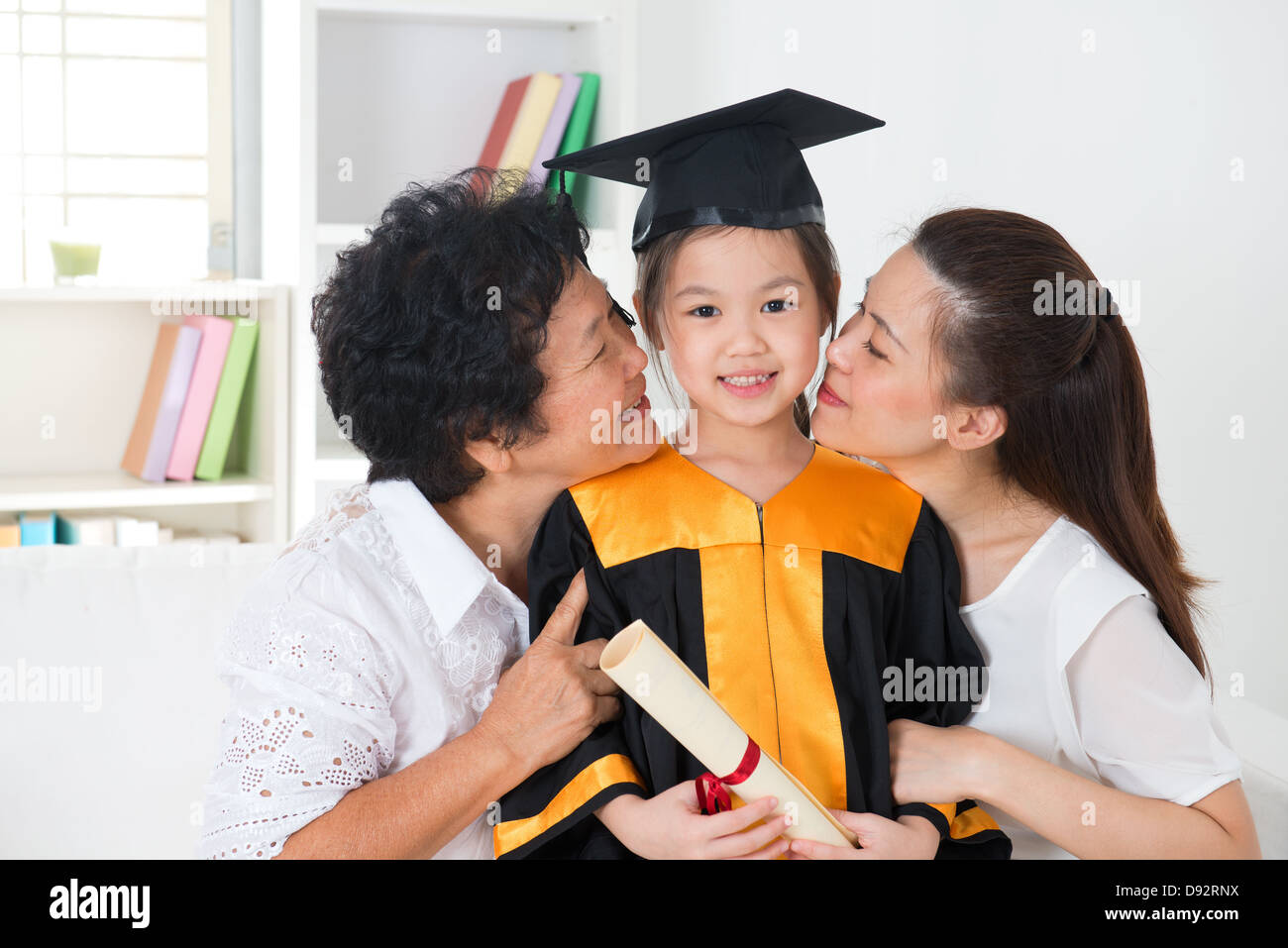 Kindergarten graduation. Asian family, grandparent and parent kissing ...