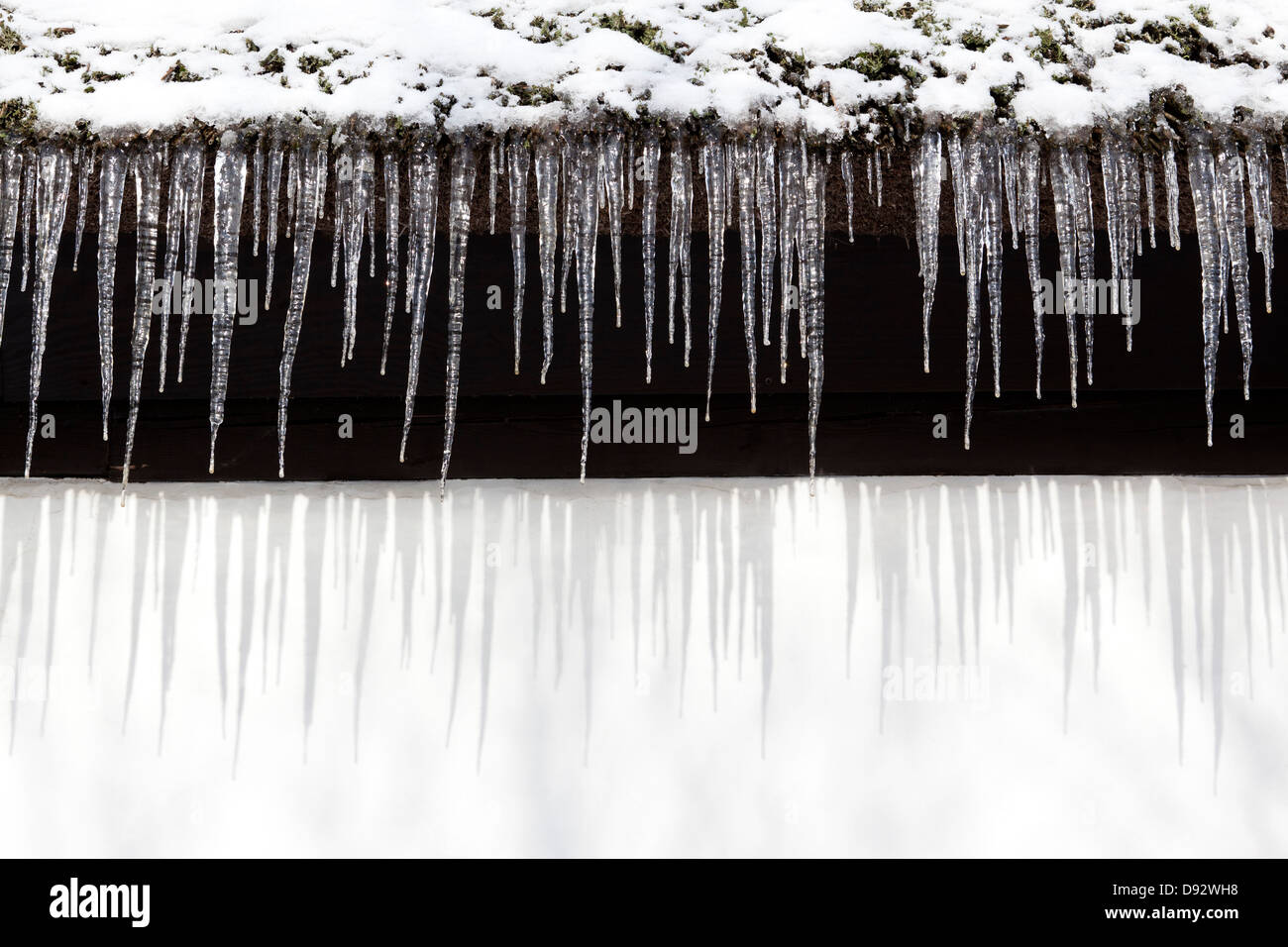 Snow and a row of icicles hanging from the eaves of a building Stock ...