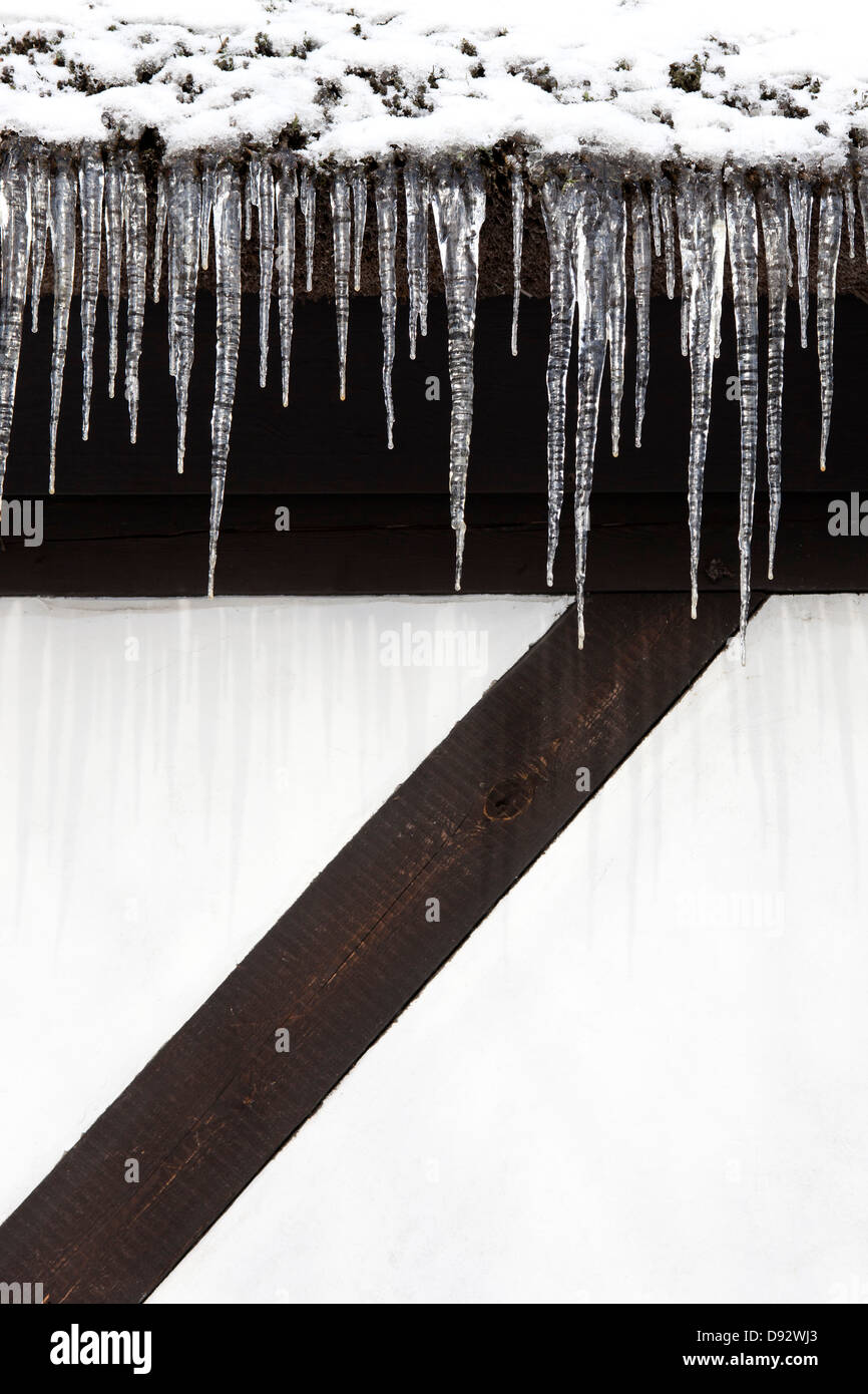 Snow and a row of icicles hanging from the eaves of a building Stock ...
