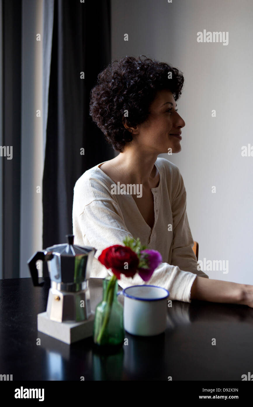 A smiling woman looking away while sitting at a table Stock Photo - Alamy