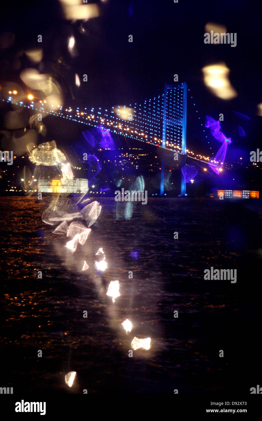 Reflected light and view of an illuminated bridge over water at night ...