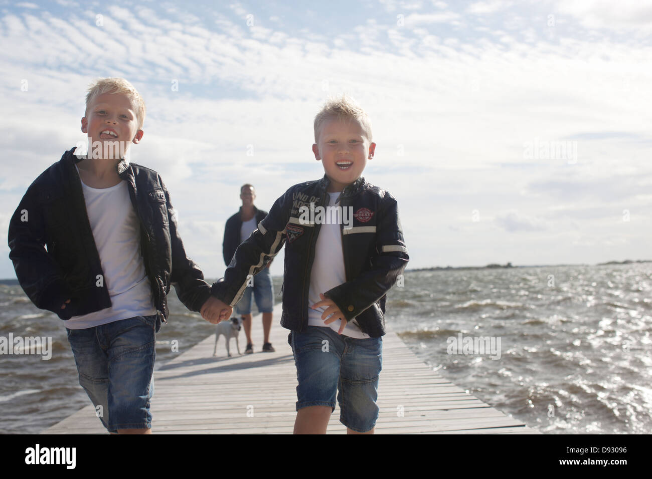 Two boys on jetty, father in background Stock Photo - Alamy
