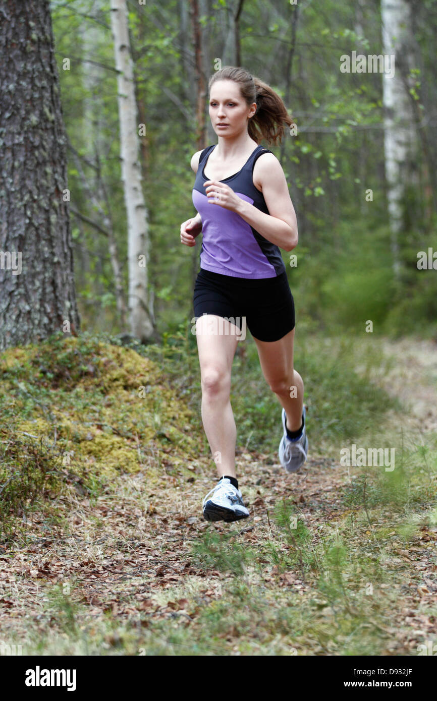 Young woman running through forest Stock Photo - Alamy
