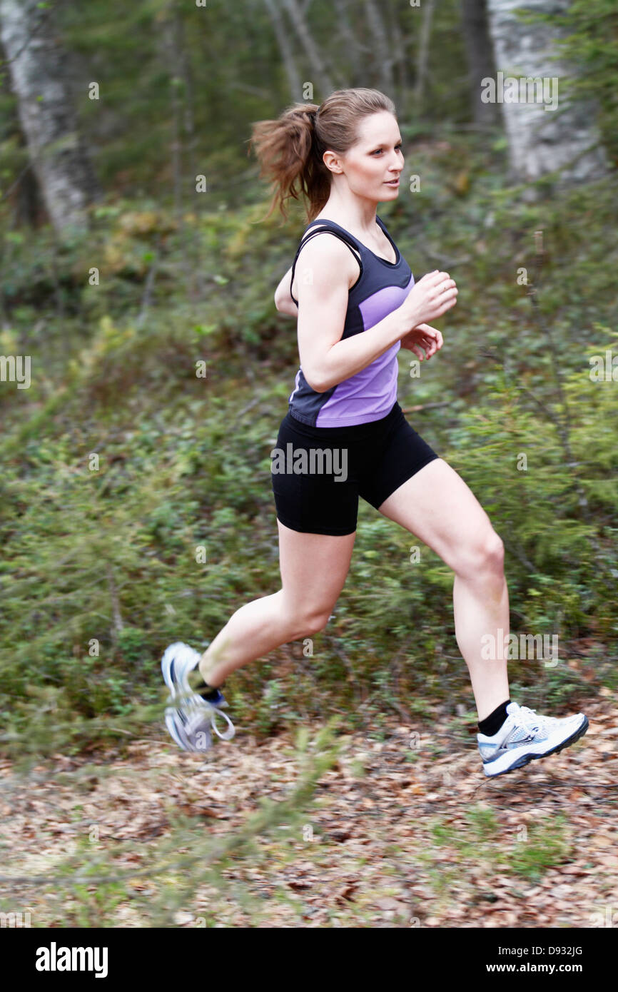 Young woman running through forest Stock Photo - Alamy
