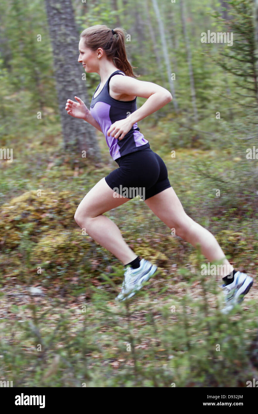Young woman running through forest Stock Photo - Alamy