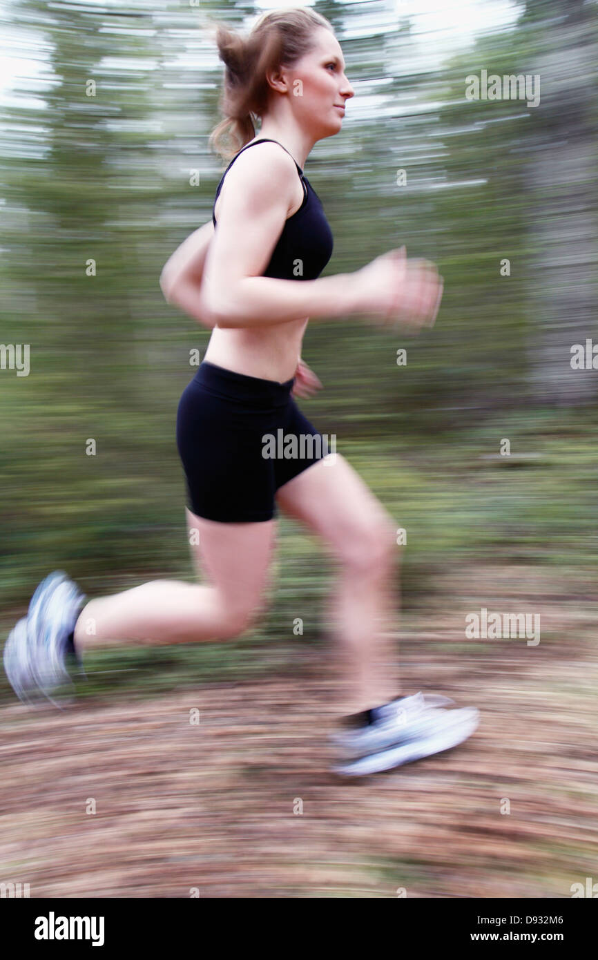 Young woman running through forest Stock Photo - Alamy