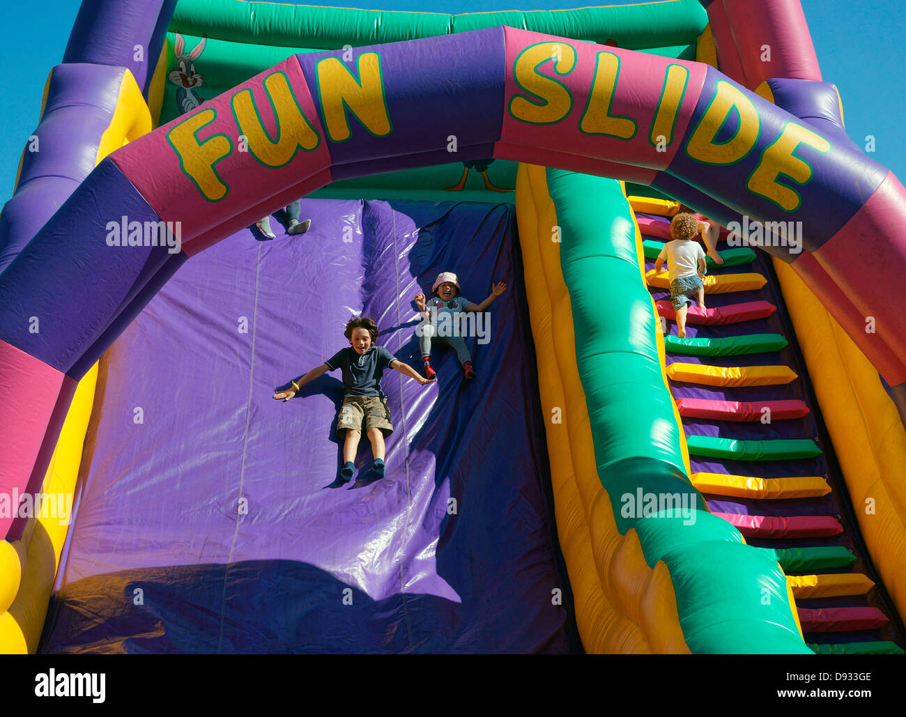 Young children descending a colourful, inflatable fun slide, at an ...