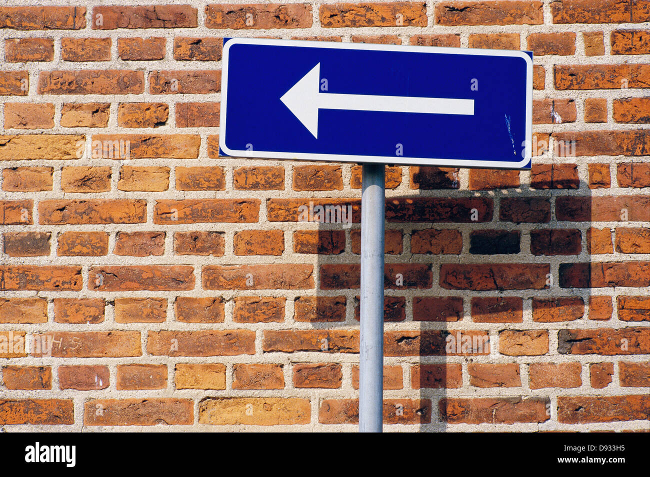 Arrow sign board against bricked wall Stock Photo - Alamy