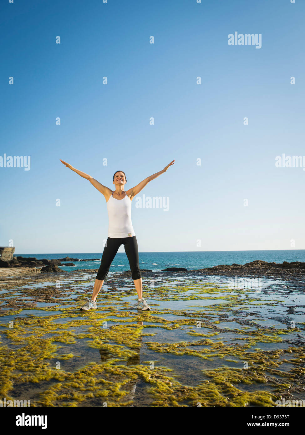 Mixed race runner stretching on rocky beach Stock Photo - Alamy