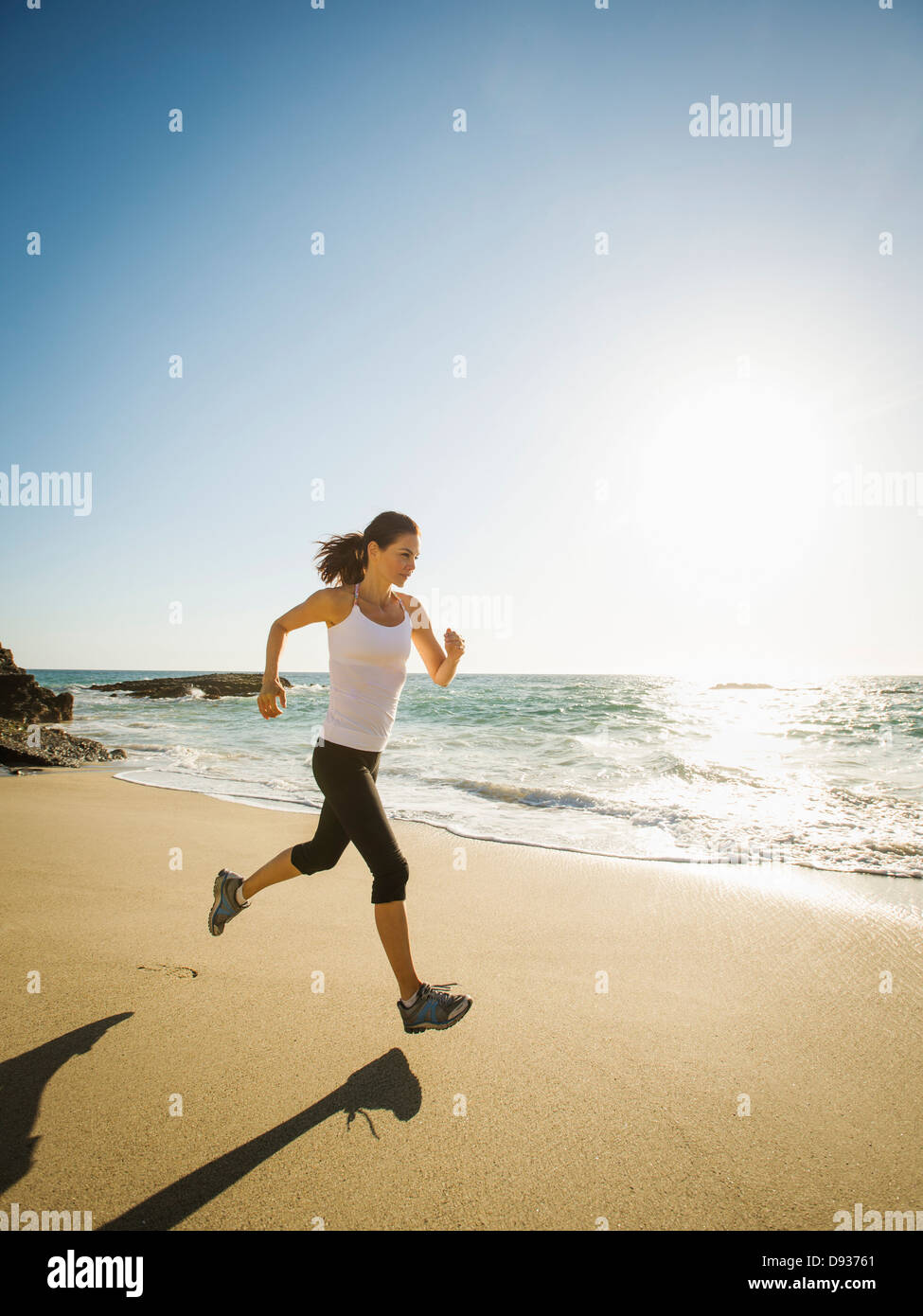Mixed race woman running on beach Stock Photo - Alamy