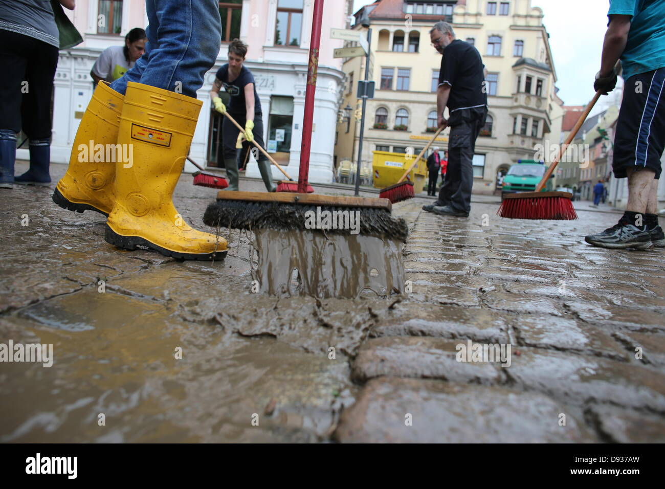 Helpers clear streets from mud swept in by floodwater of the Elbe river ...