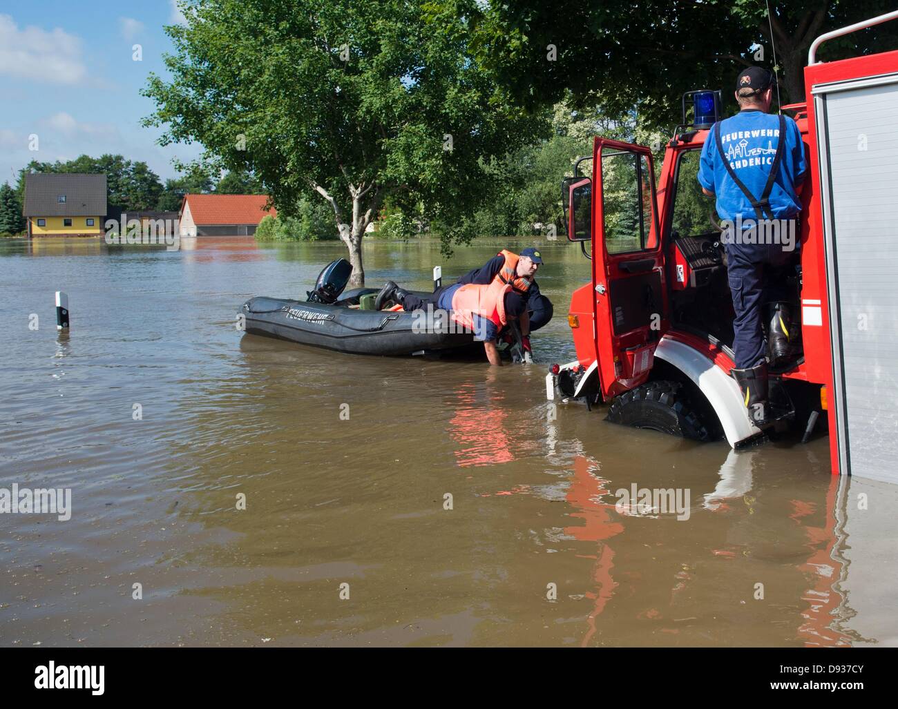 Fire fighters drive across flooded streets with a rubber boat in the ...