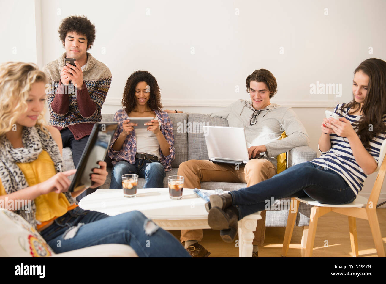 Friends using technology in living room Stock Photo - Alamy