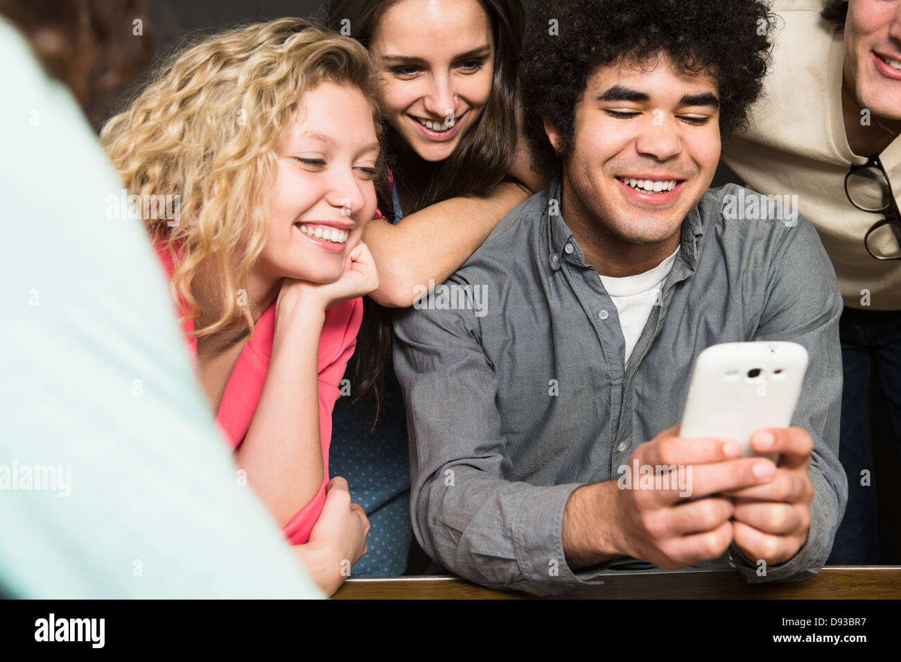 Friends using cell phone together Stock Photo - Alamy