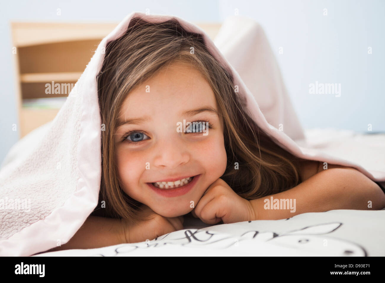 Caucasian girl smiling under covers Stock Photo - Alamy