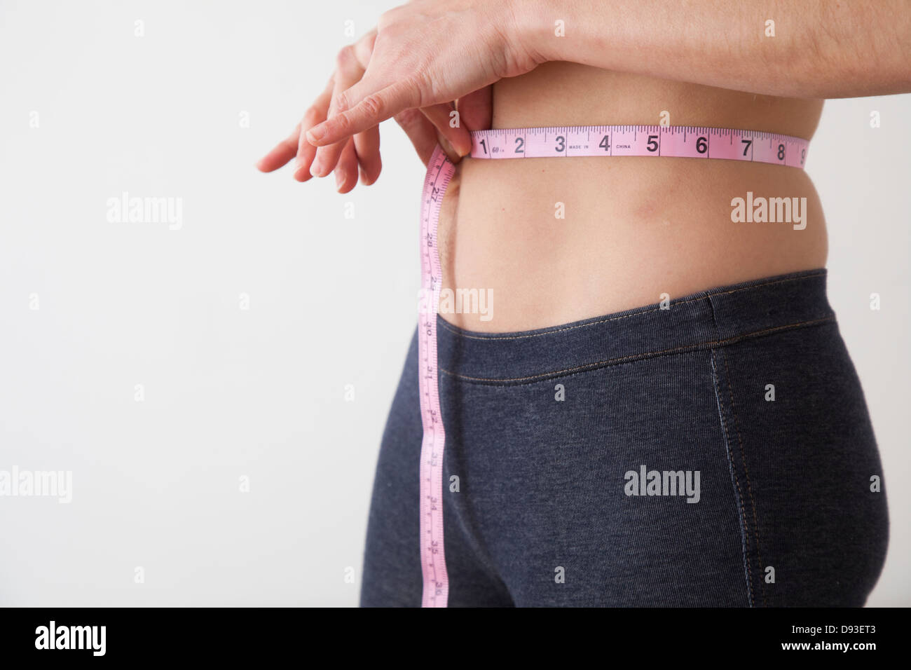 Caucasian woman measuring her waistline Stock Photo - Alamy