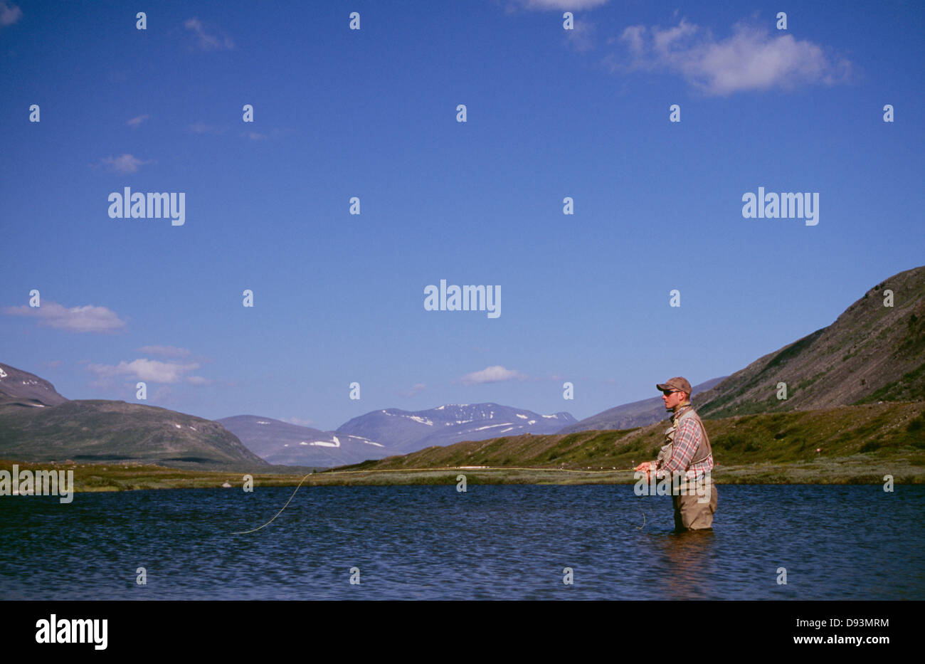 Young man fishing with mountains in background, side view Stock Photo ...