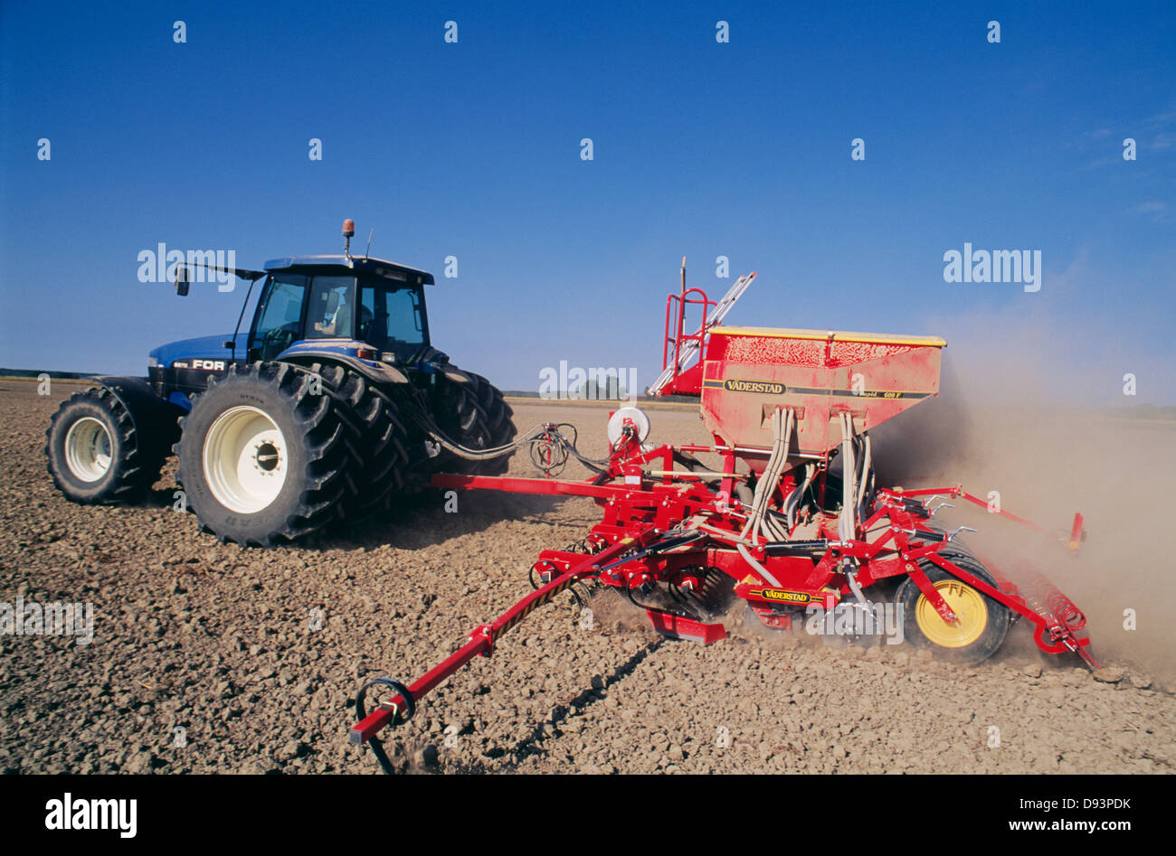 Farm worker tilling field with tractor Stock Photo - Alamy