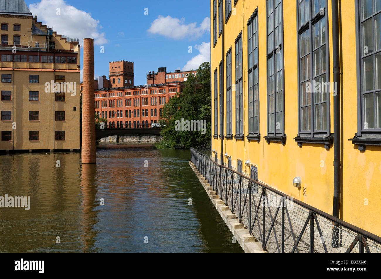 Factory buildings by river Stock Photo - Alamy