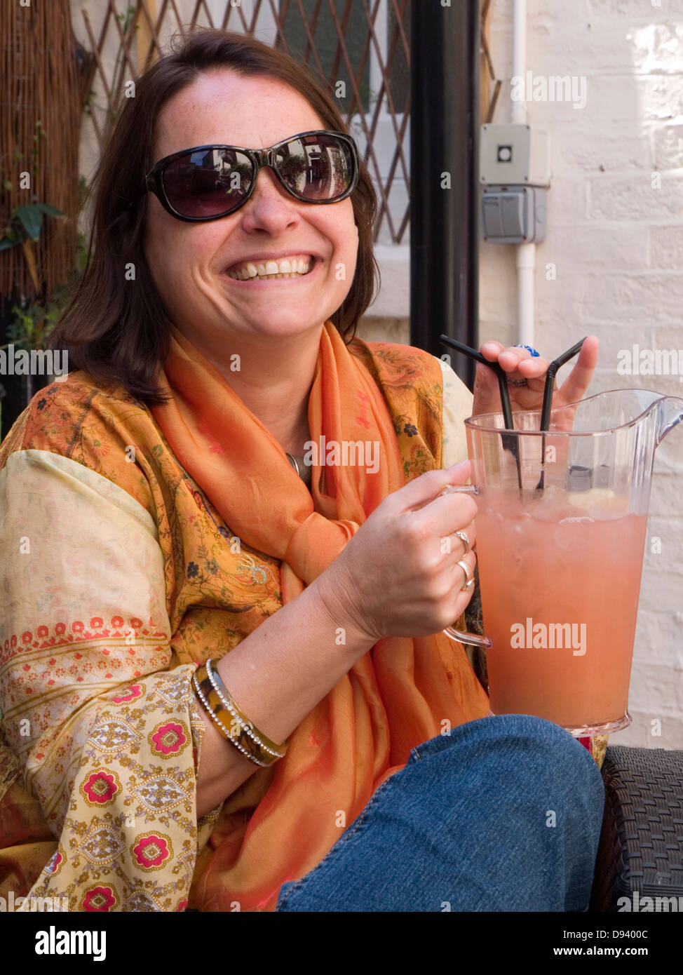 smiling happy woman sitting in pub garden with large cocktail jug Stock ...