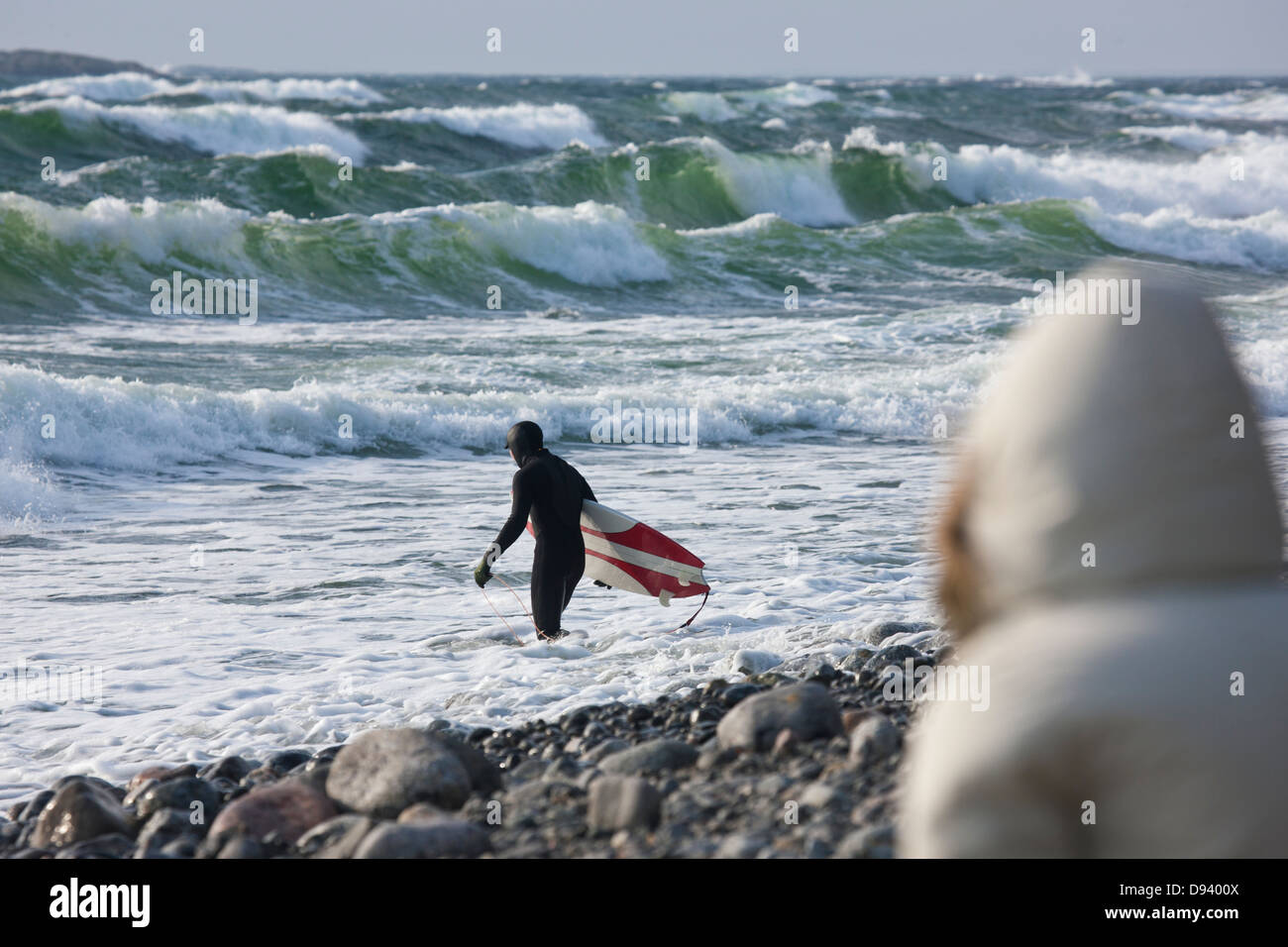Surfer carrying surfboard in wavy sea Stock Photo - Alamy