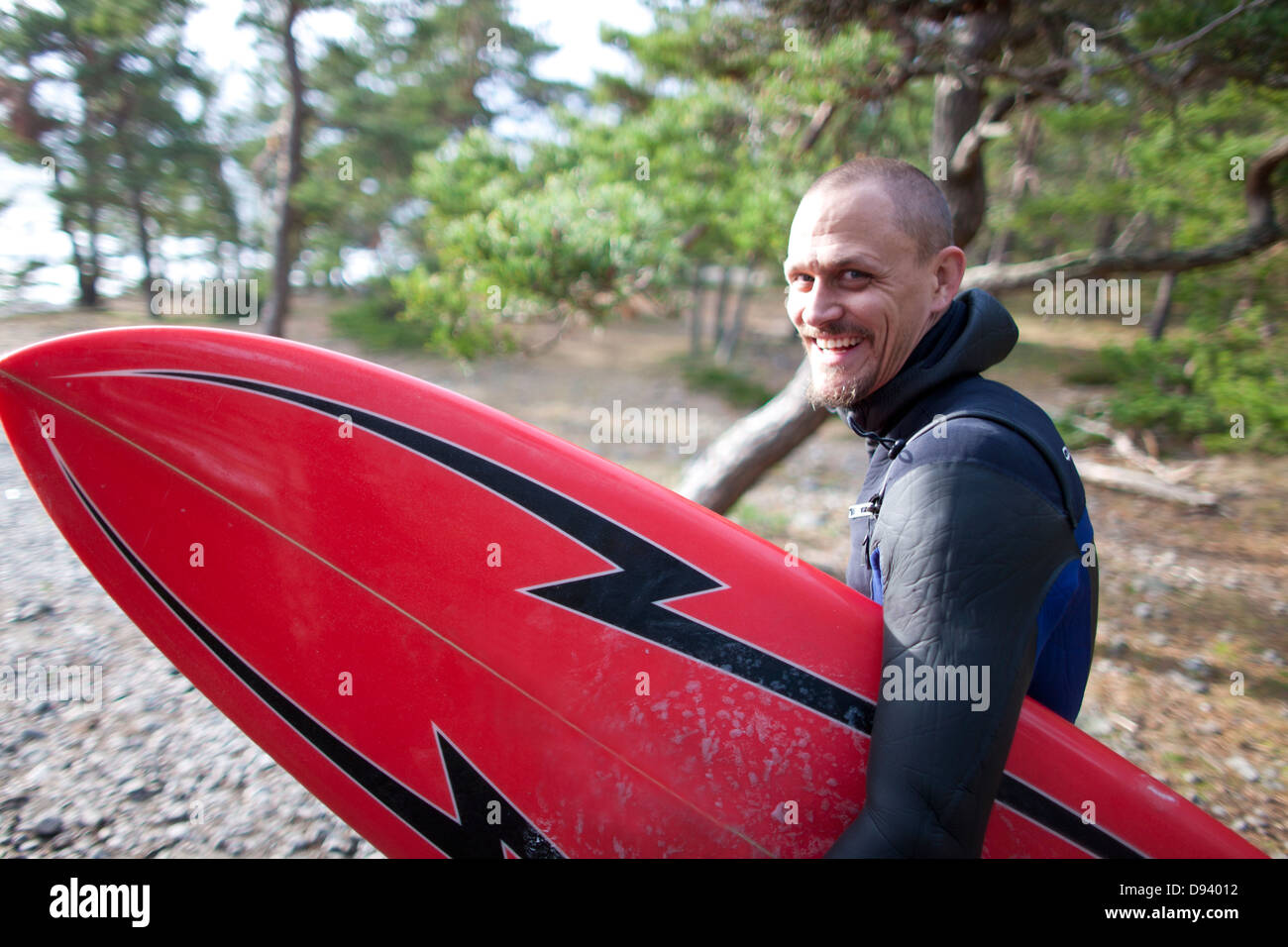 Portrait of smiling surfer carrying surfboard Stock Photo - Alamy