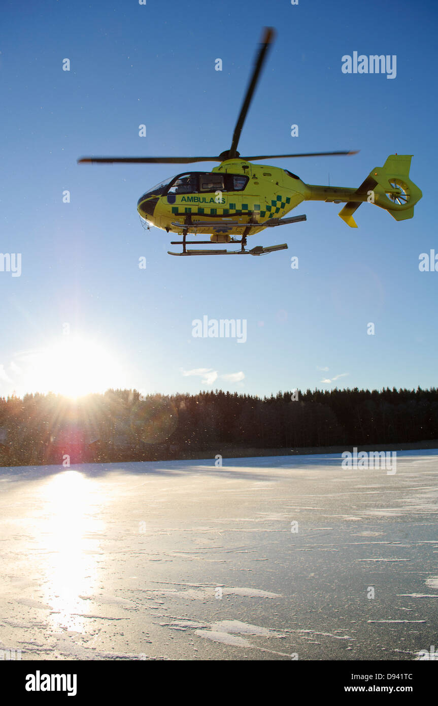 Medical rescue helicopter flying over frozen river Stock Photo - Alamy