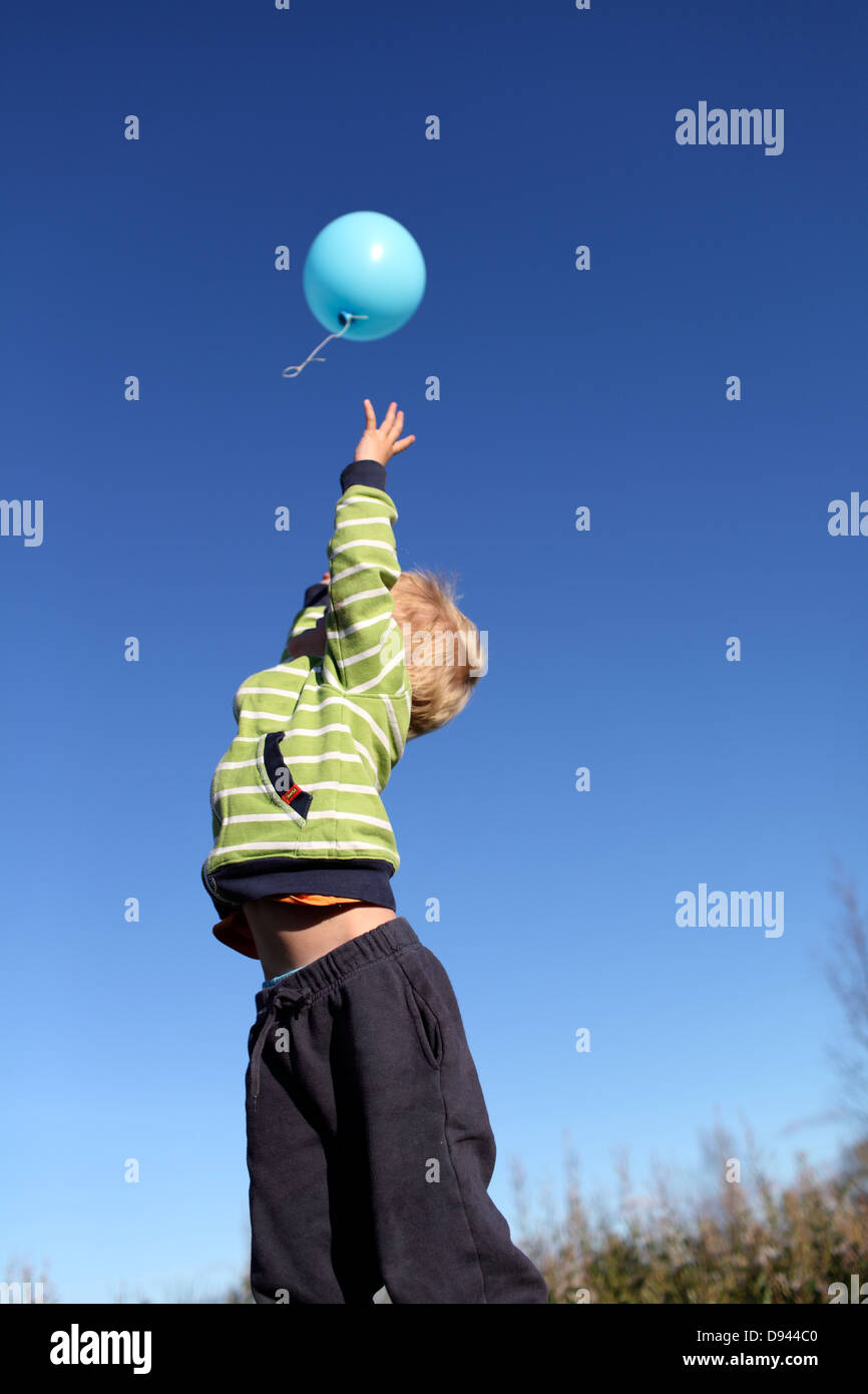 Boy throwing blue balloon Stock Photo - Alamy