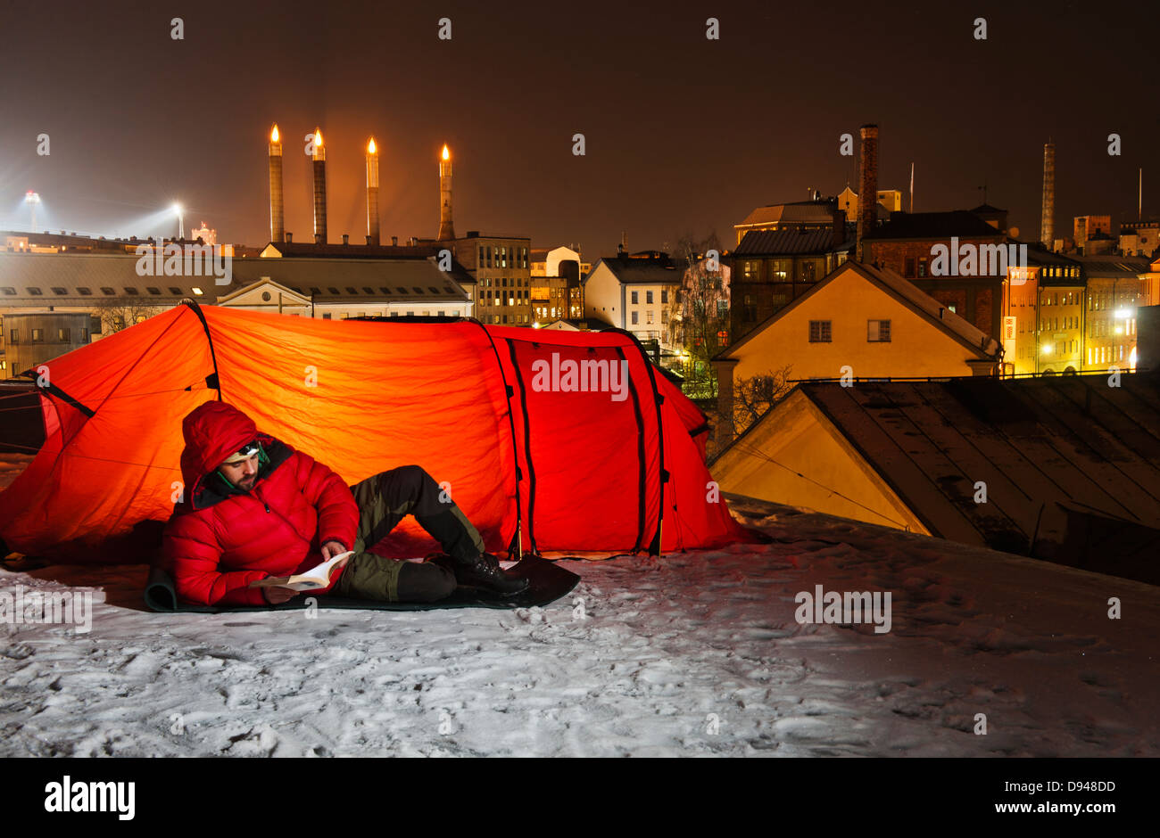 Man reading book in front of tent on roof of building Stock Photo - Alamy
