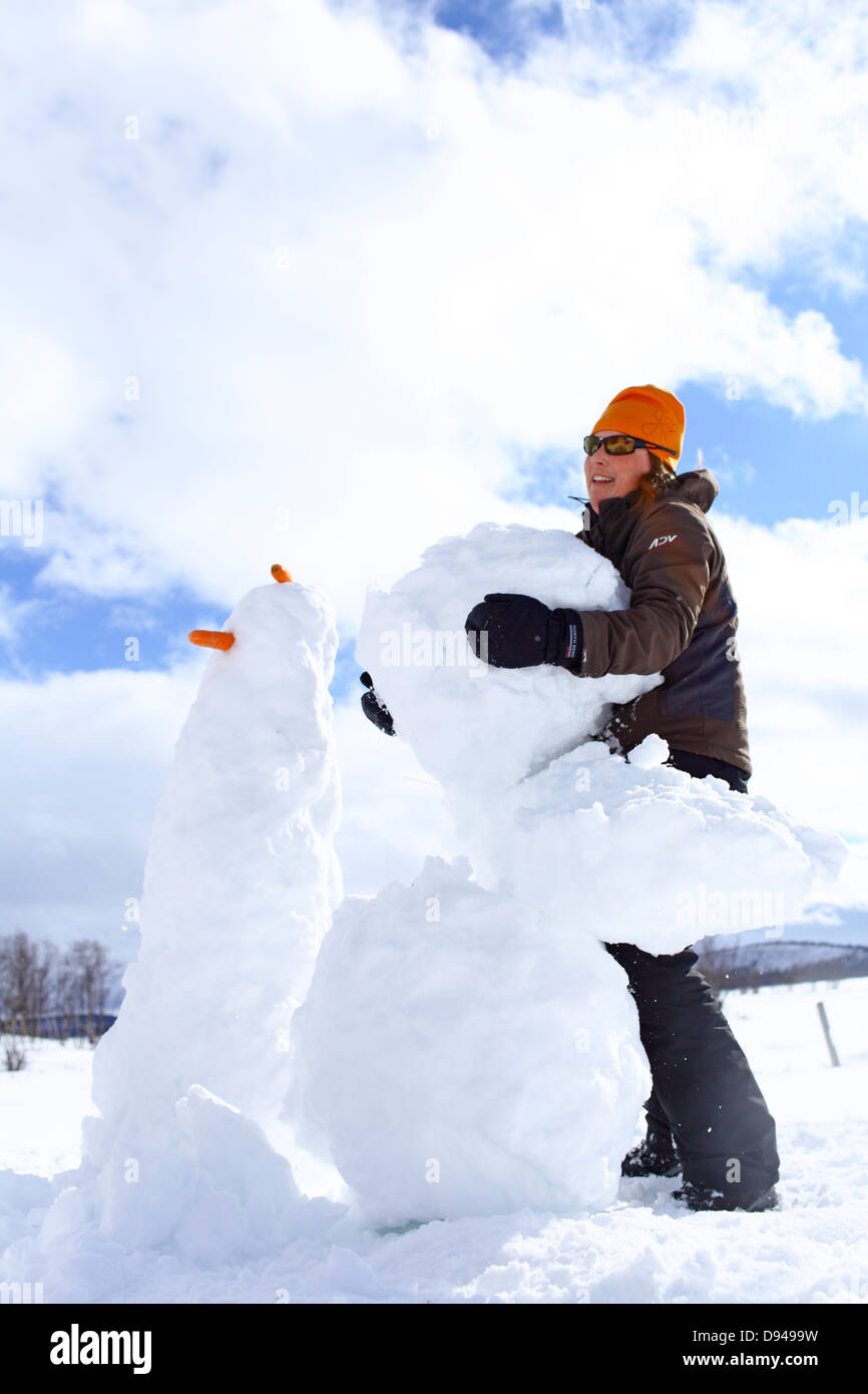 Woman building snowman Stock Photo - Alamy