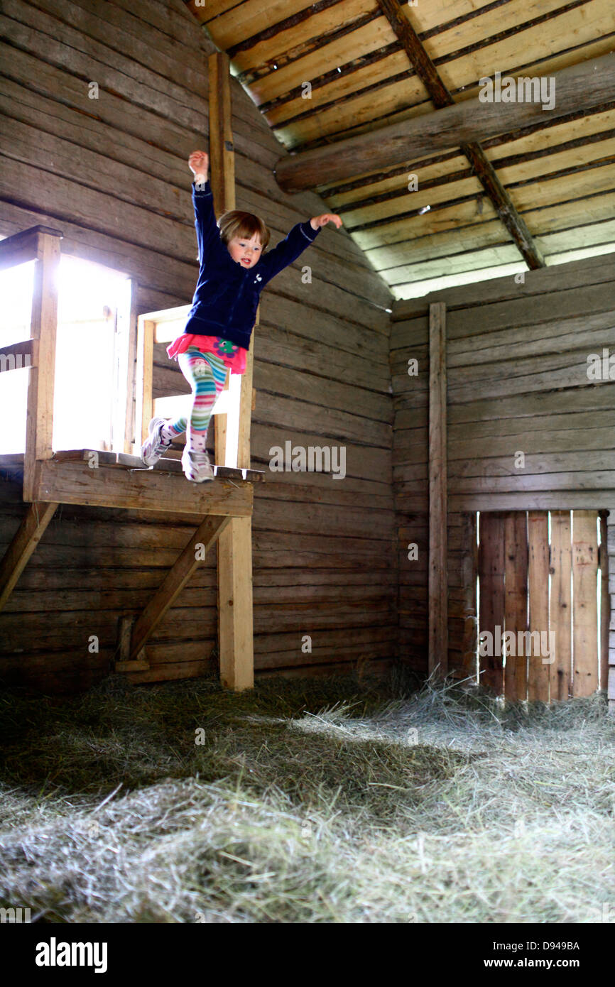 Girl jumping on hay in barn Stock Photo - Alamy