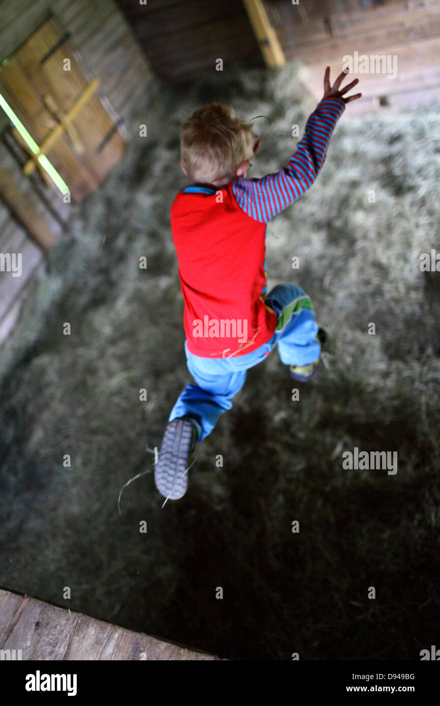 Child jumping on hay in barn Stock Photo - Alamy