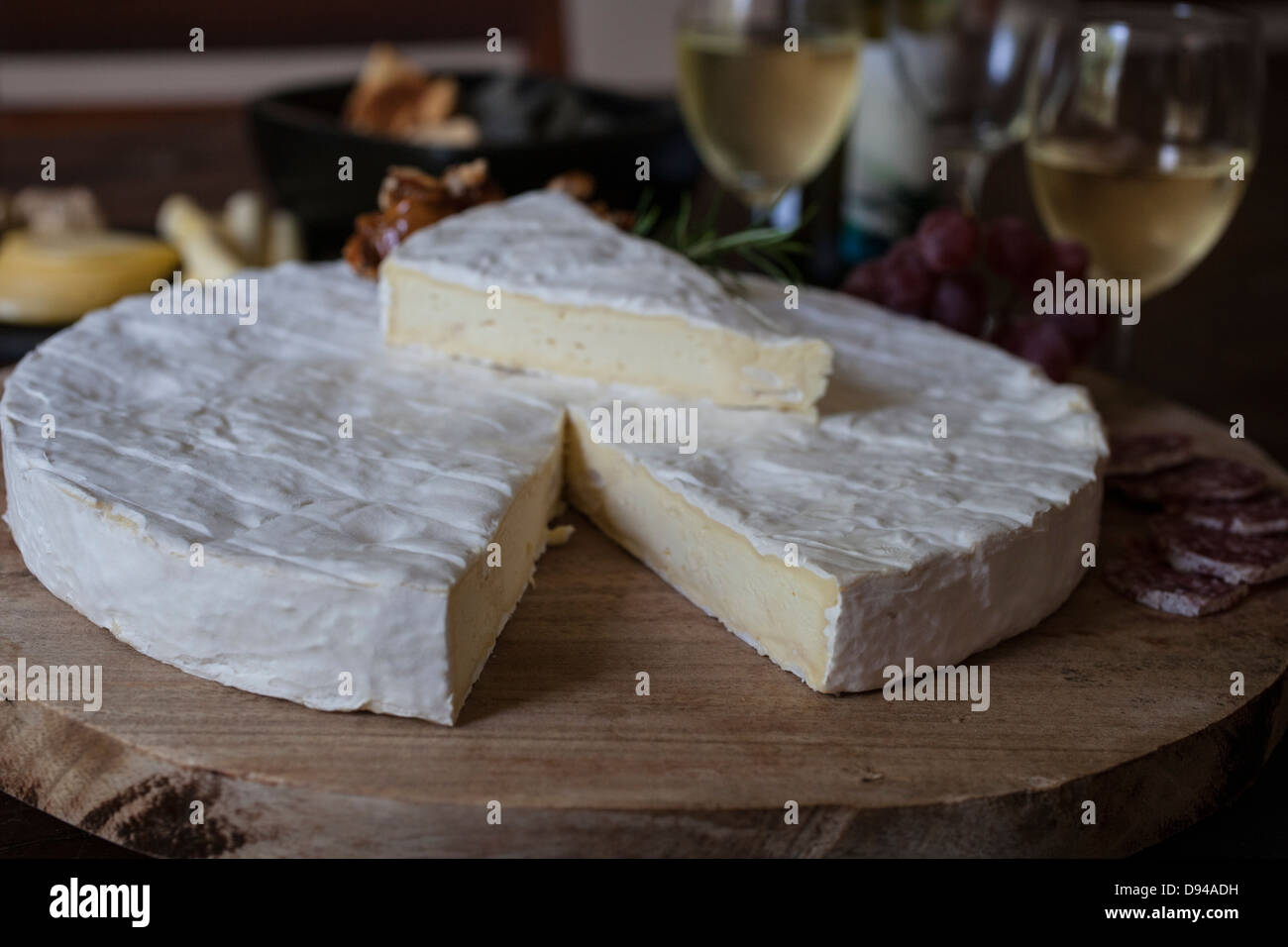wheel of brie cheese with white wine and salamie Stock Photo - Alamy