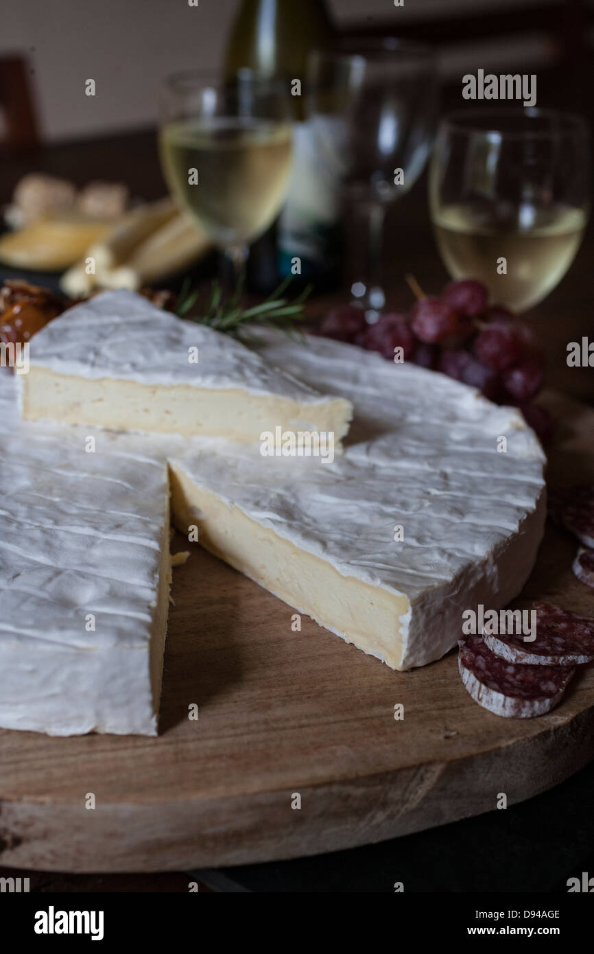 wheel of brie cheese with white wine and salamie Stock Photo - Alamy