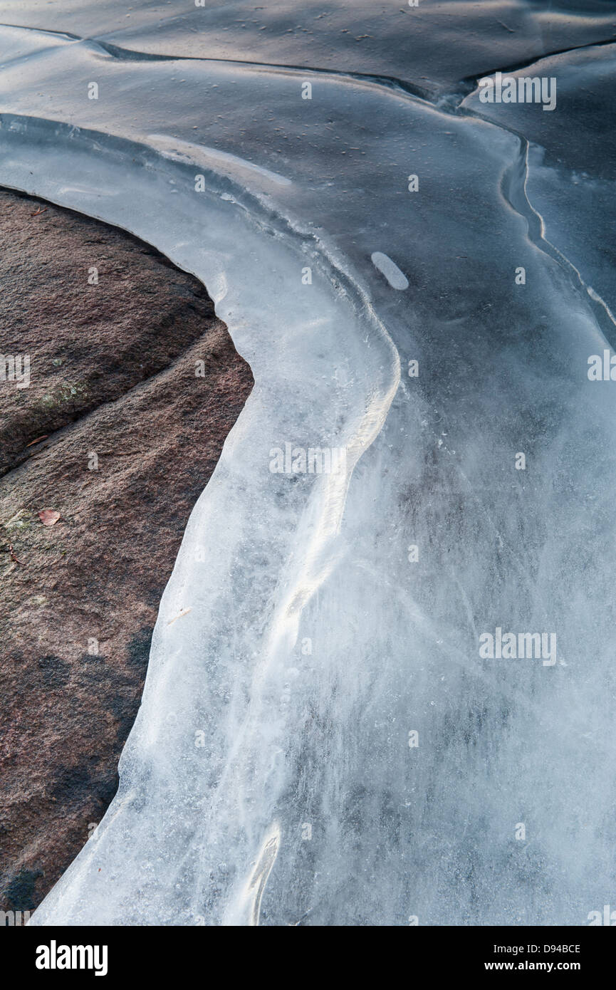 Frozen lake meeting rock Stock Photo - Alamy