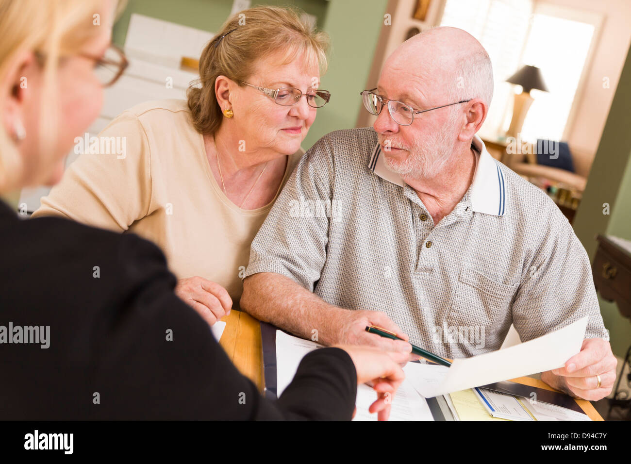 Senior Adult Couple Going Over Papers in Their Home with Agent Stock ...