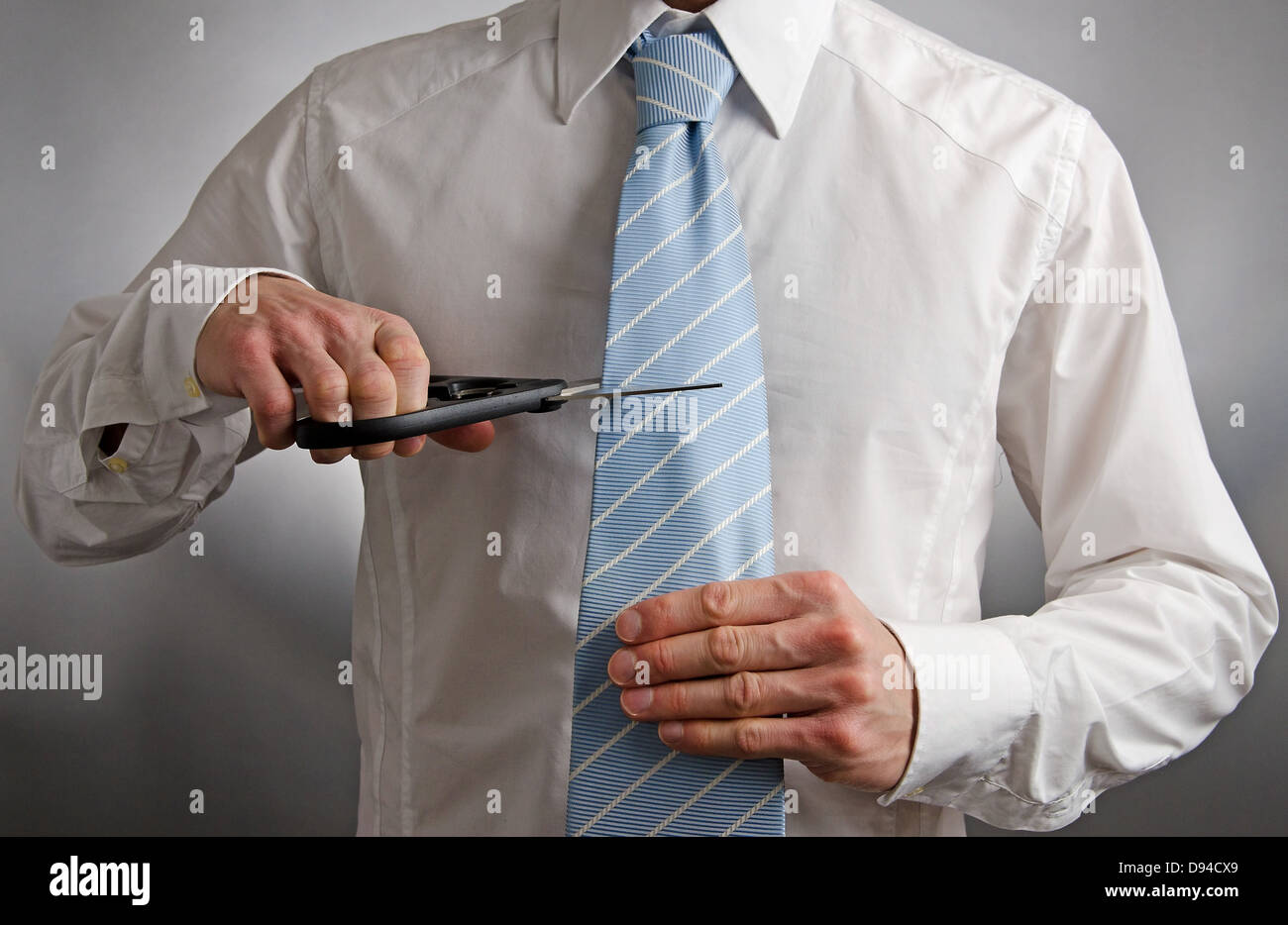Image of a man about to cut off his tie Stock Photo - Alamy