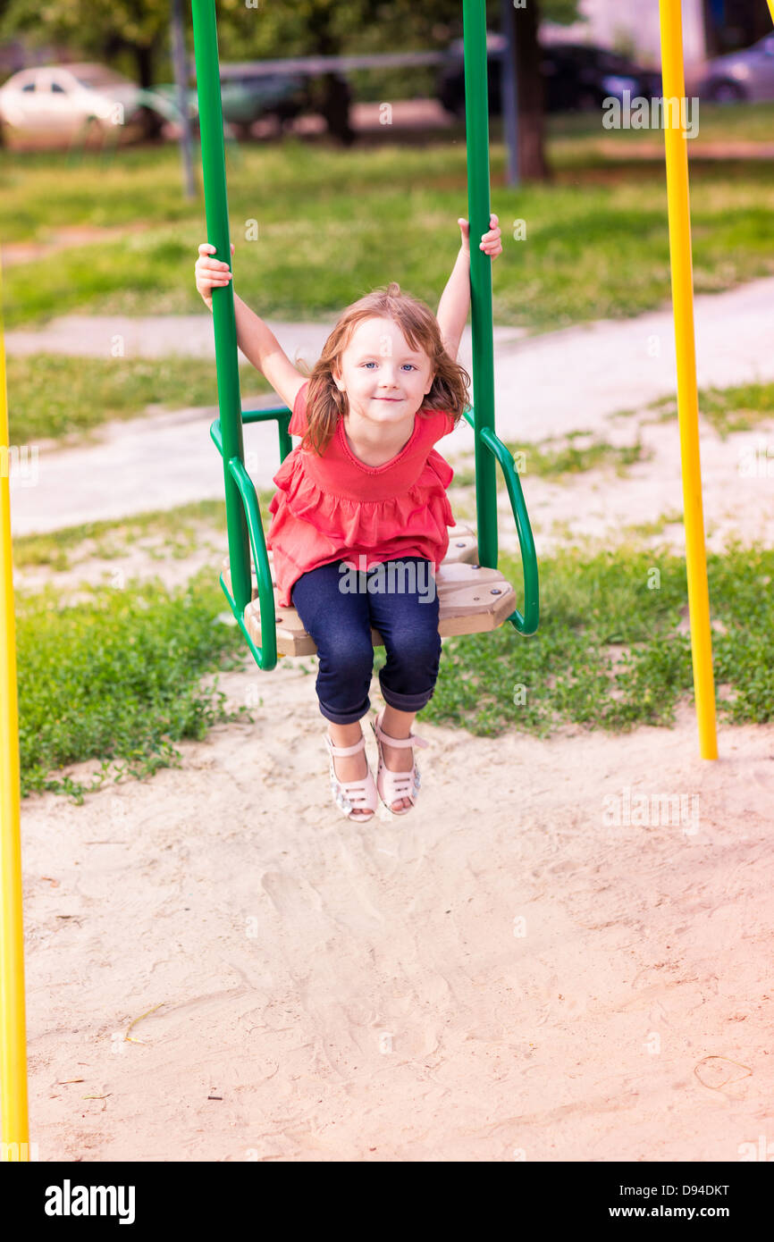 Beautiful little girl on a swings outdoor in the playground at summertime Stock Photo - Alamy