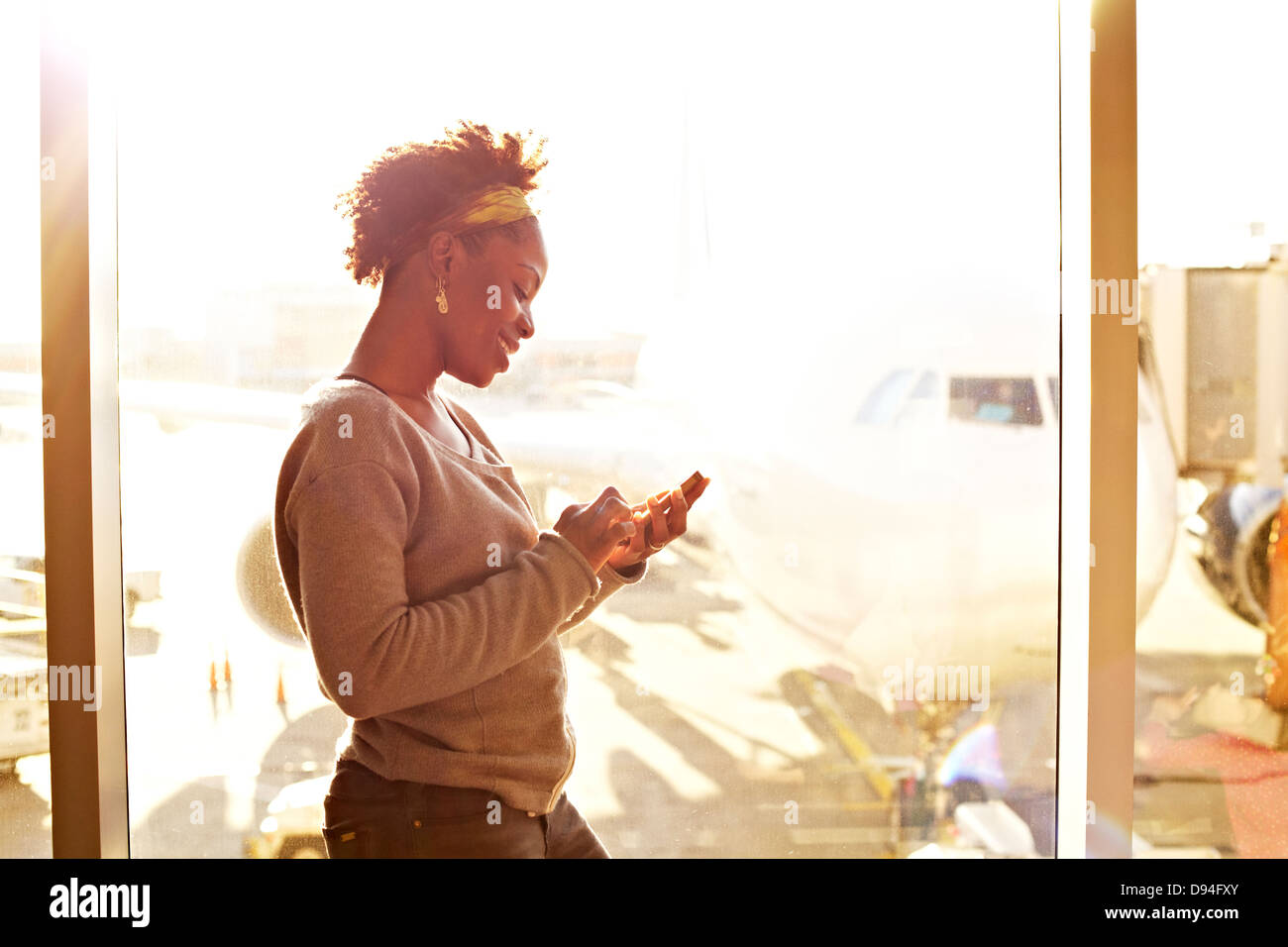 Black woman using cell phone in airport Stock Photo - Alamy