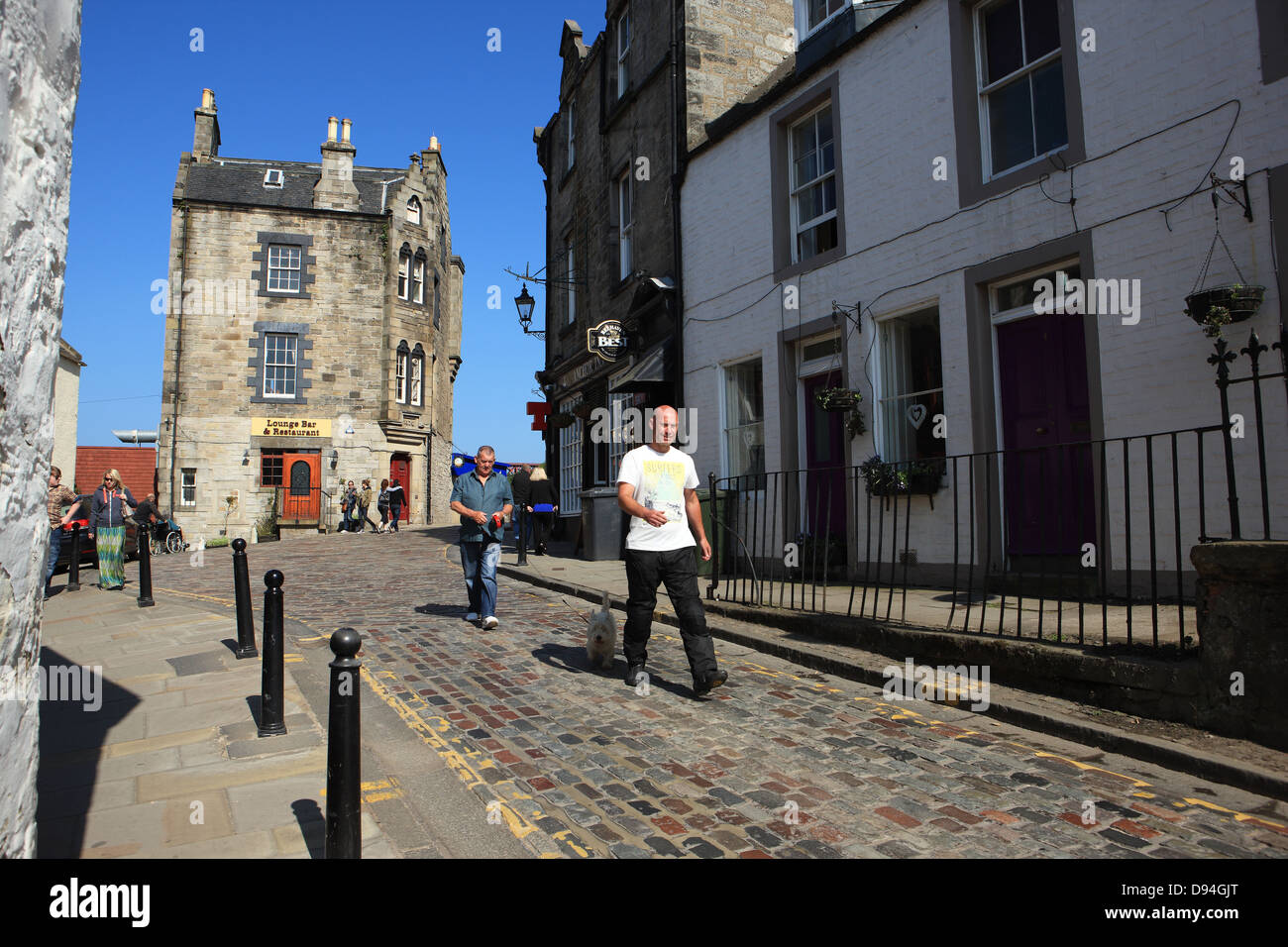 People walking down the cobbled street through the coastal town of ...