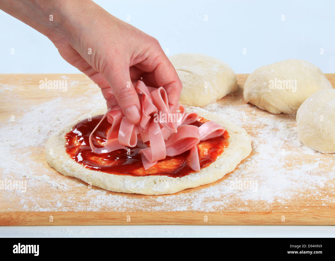 Cook topping pizza with slices of ham Stock Photo - Alamy